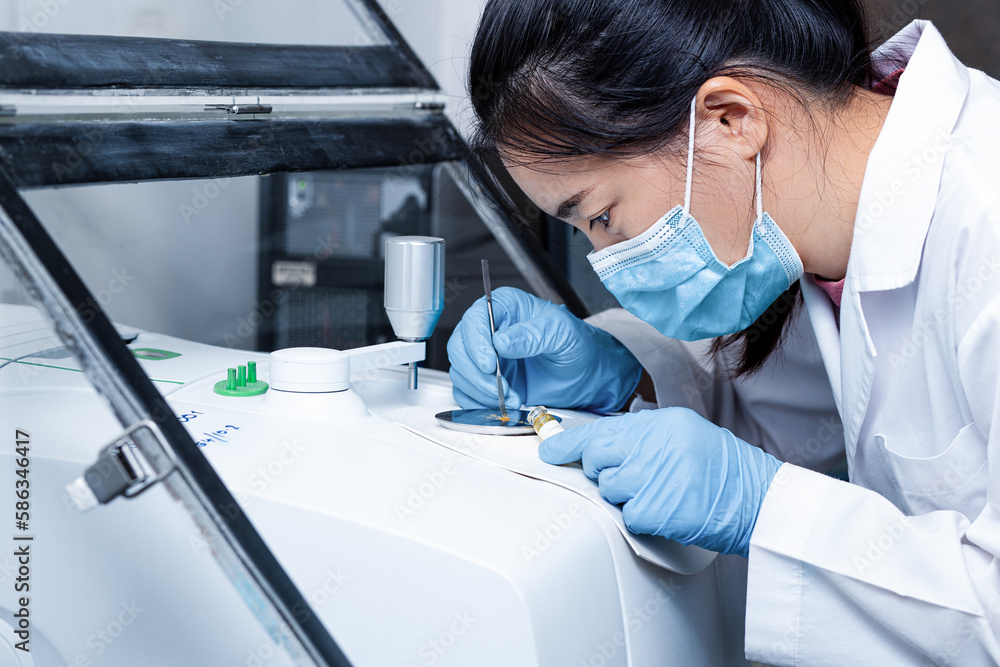 Scientist female using a stainless spatula to scoop substances put to ...