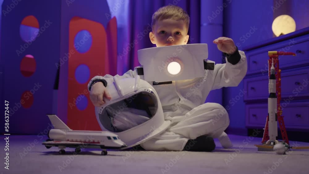 Portrait cute boy in spacesuit, holding an astronaut helmet in his ...