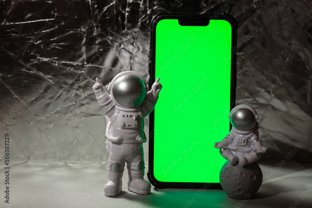 Plastic toy figure astronaut with mobile phone chroma key green screen ...