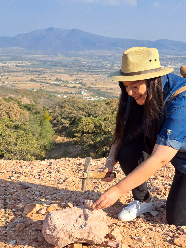 Latina woman with hat and miner's pick hammer works as a geologist ...