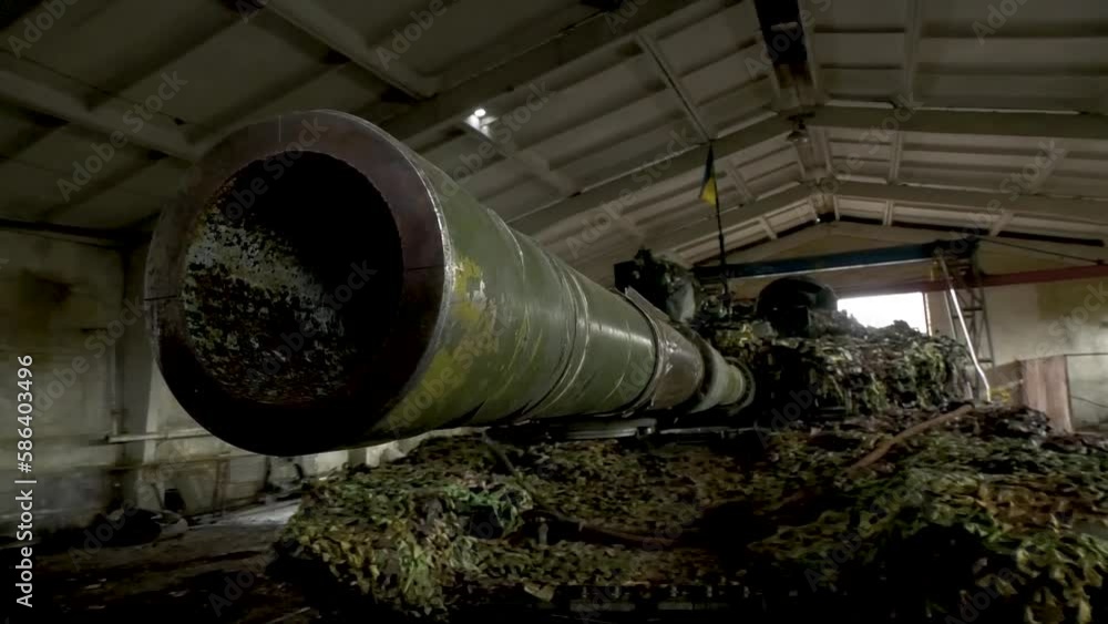 The muzzle of the tank slowly turns to the side. A tank in a hangar in ...