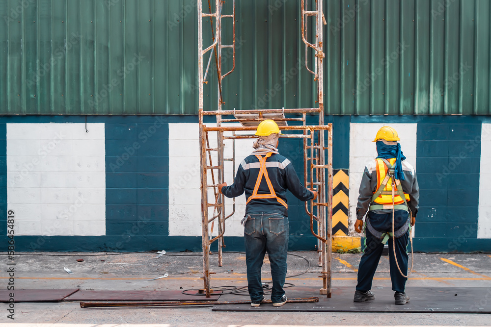 Construction worker wearing safety harnesses with Scaffolding at ...