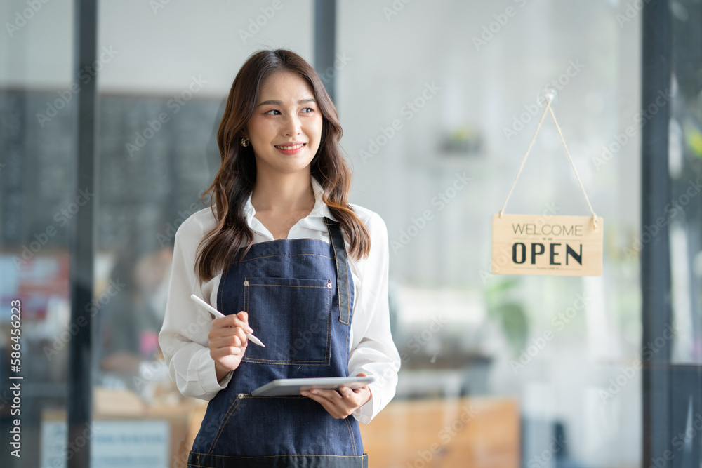 Asian female worker or barista standing smiling and holding the tablet ...