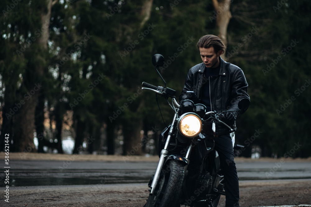male biker motorcyclist in a leather jacket sits on a vintage ...
