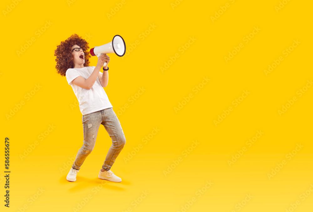 Cheerful funny preteen boy with loudspeaker in his hands makes loud ...