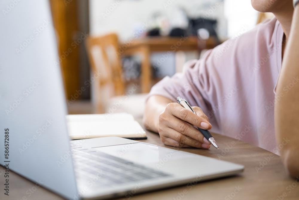 Close up hand taking notes. Asian woman in online learning enjoying ...