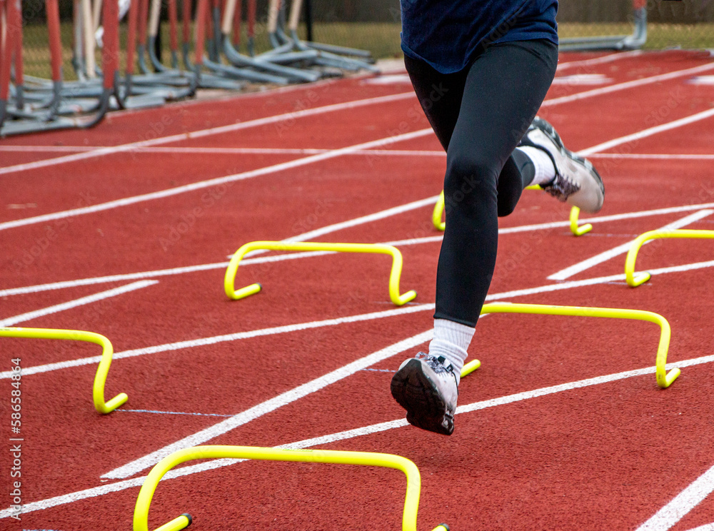 Legs of a runner running over six inch yellow hurdles on a track Stock ...