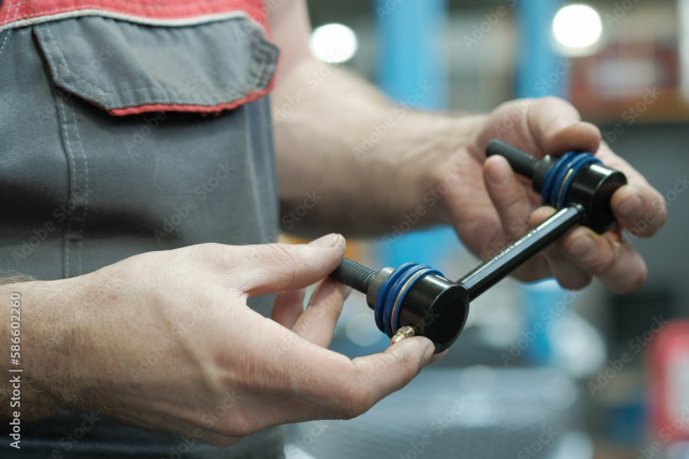Auto parts. The mechanic holds in his hands the stabilizer bar of the ...