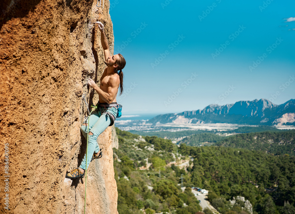 Strong muscular body man rock climber climbing on height vertical rock ...
