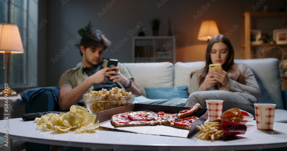 Bored young couple is frustrated after hard day, sitting in front of tv ...