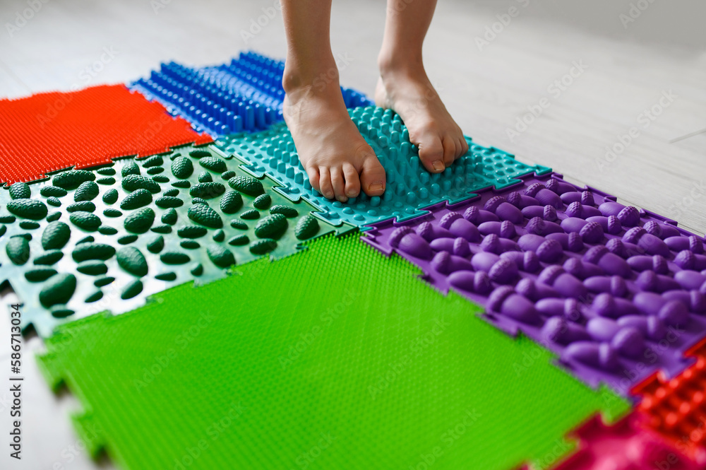 The child walks barefoot on an orthopedic massage mat for feet of ...