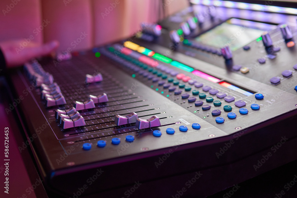 An expert adjusting audio mixing console with white blank screen laptop ...