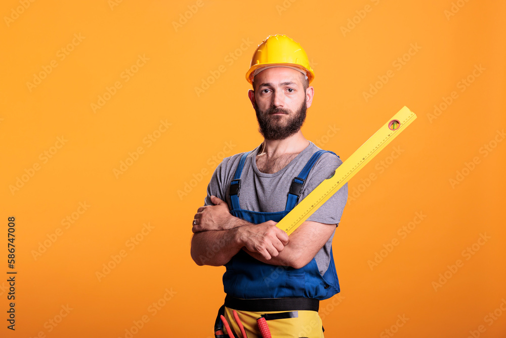 Construction worker holding water level ruler in studio, posing with ...