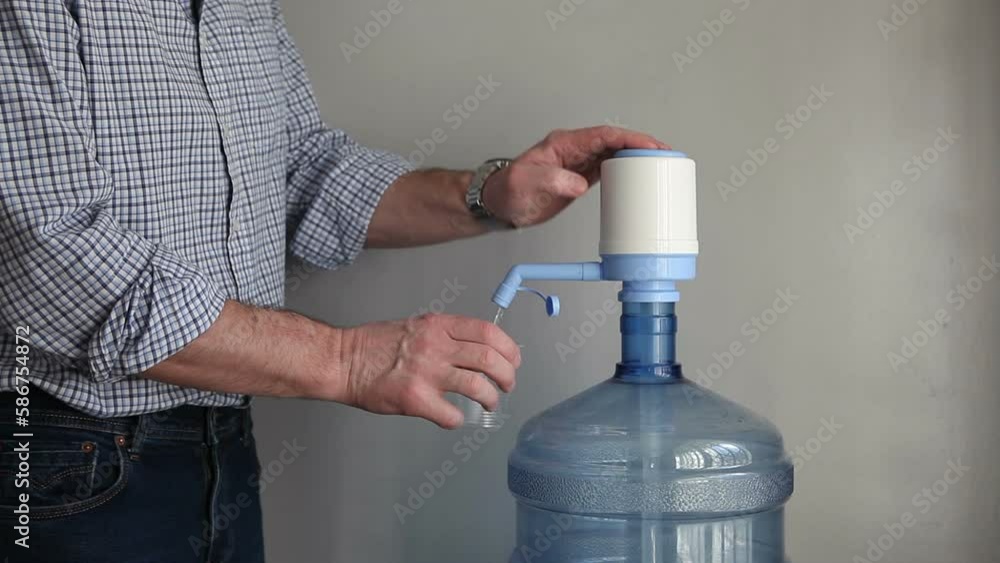 A man drinks imported bottled drinking water. A flask with artesian ...