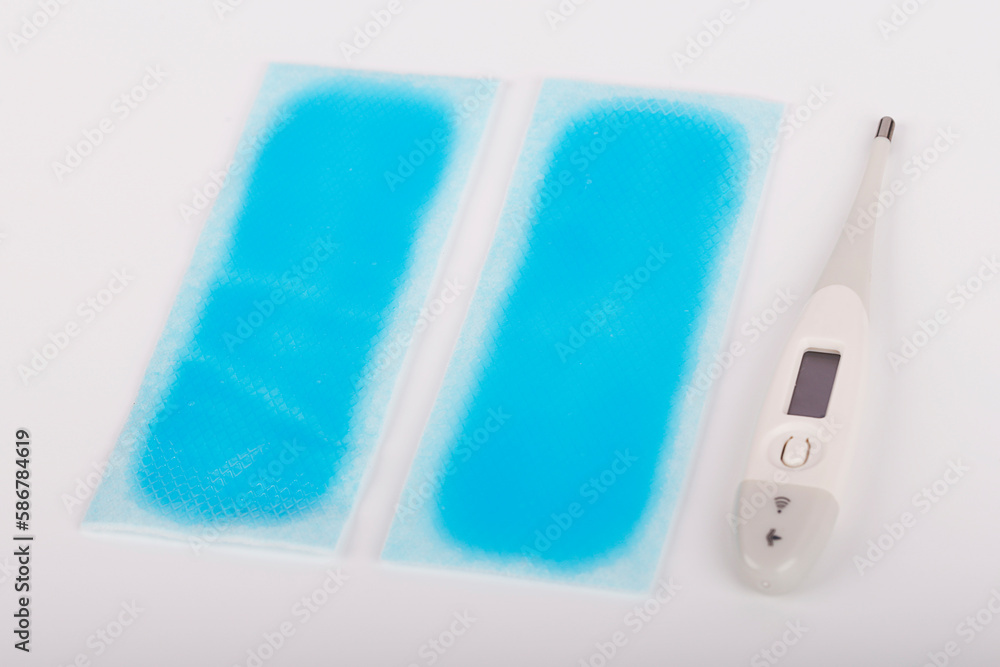 2 of cool fever pad and medical digital thermometer on white background ...