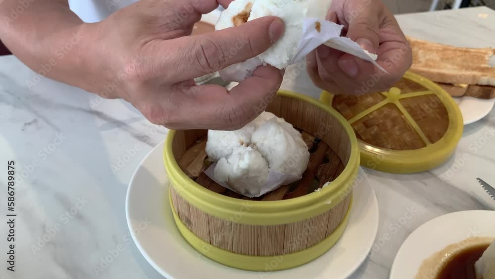 Man open up a freshly steamed hong kong dim sum style char siew pork ...