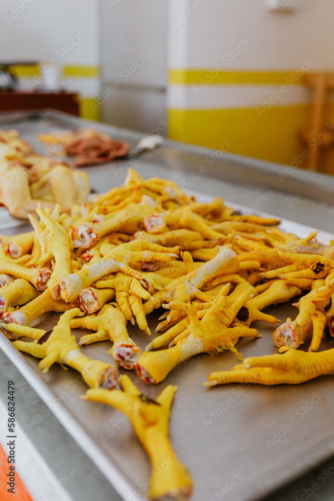 Latin Poultry shop or Polleria with raw chicken foot being sliced by ...