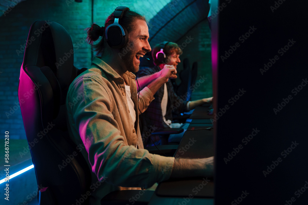 Two male gamers giving fist bump while playing video game together in ...