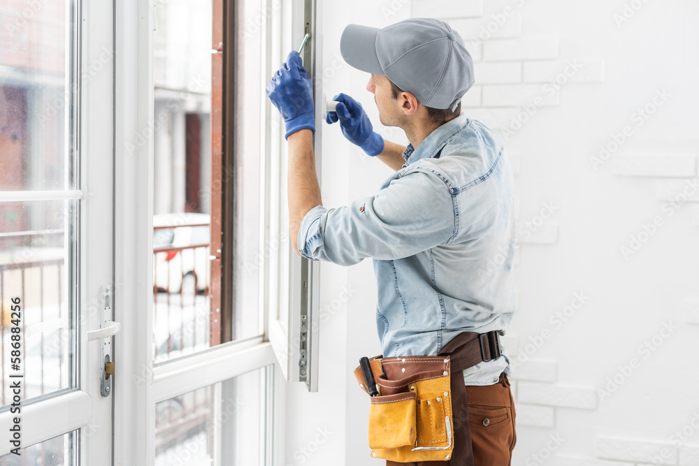 handsome young man installing bay window in a new house construction ...