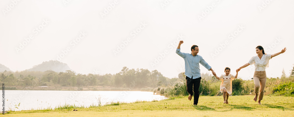 Asian family running and playing together in a beautiful nature setting ...