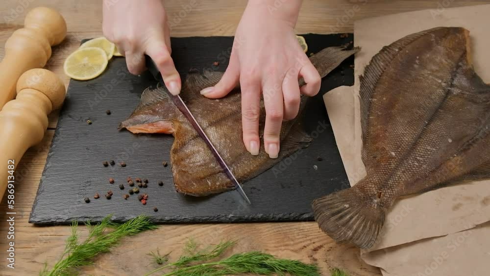 Women's hands cut dried fish from the flounder family into pieces ...