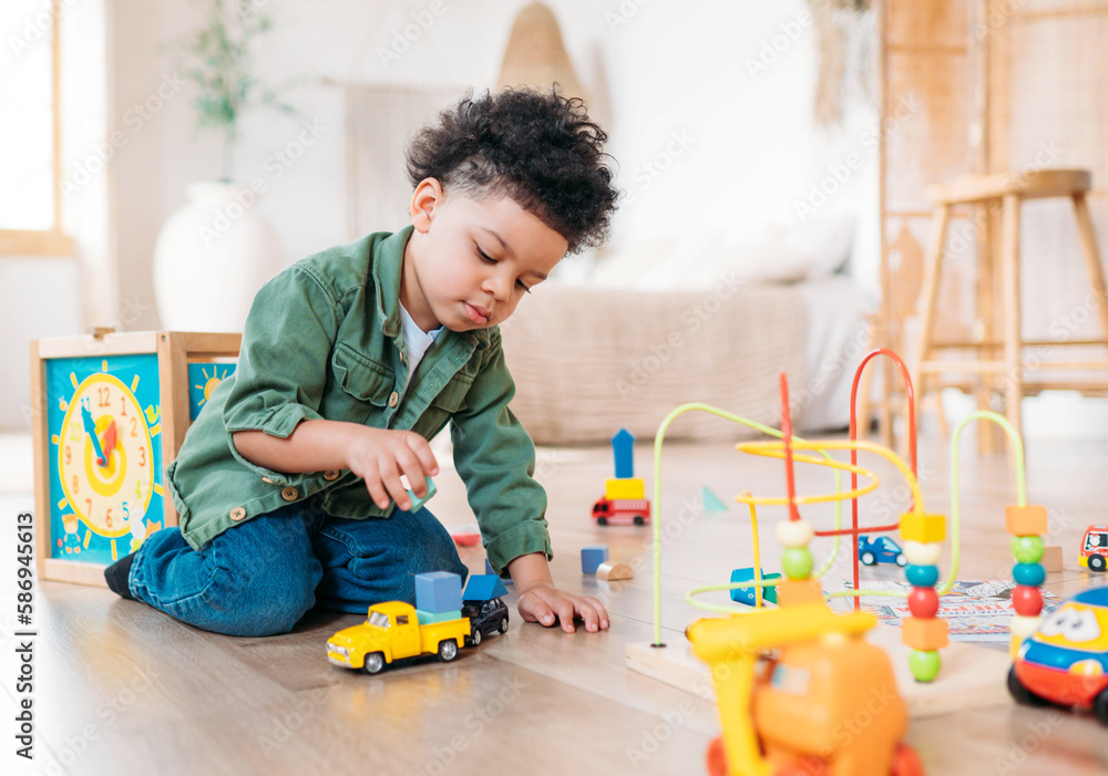 Concentrated little african american boy playing toys sitting on warm ...