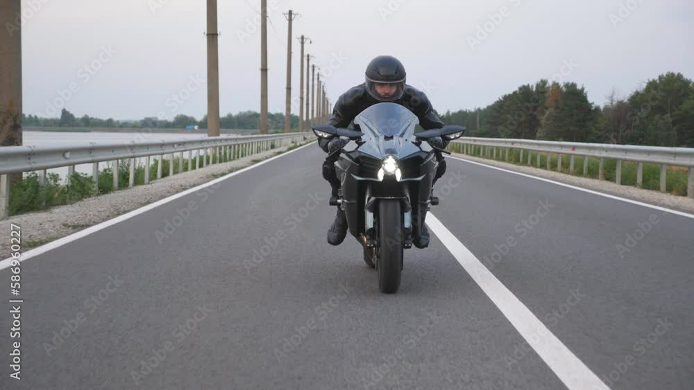 Front view to biker riding on modern sport motorbike at countryside way ...