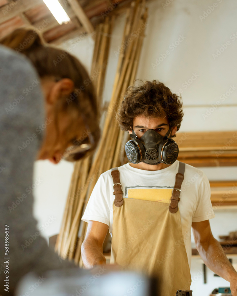 A young man working as carpenter in his wood workshop. Wood worker ...