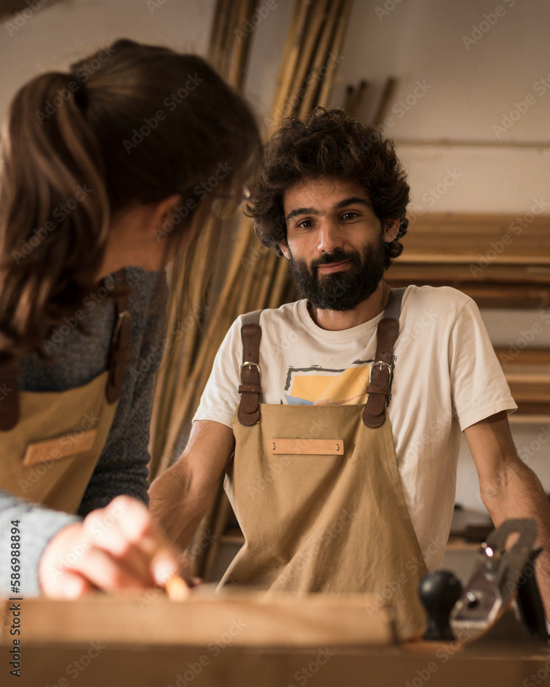 A young couple of carpenters working together in a small carpentry ...