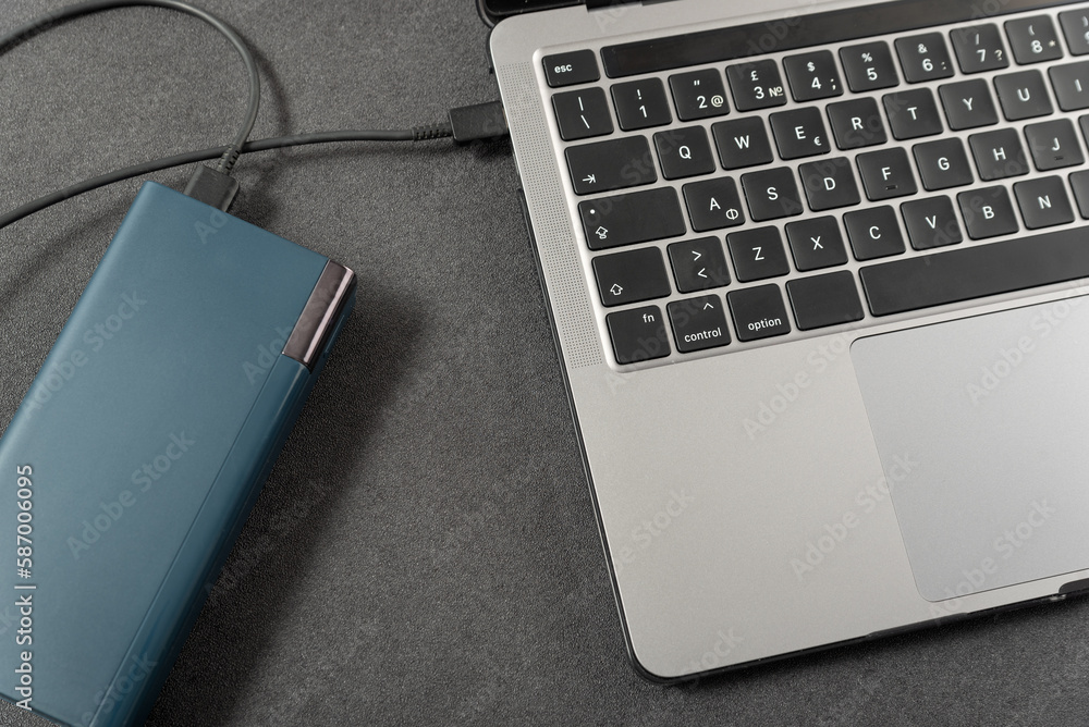 Laptop is charged by powerbank. Top view laptop is connected by cord to ...
