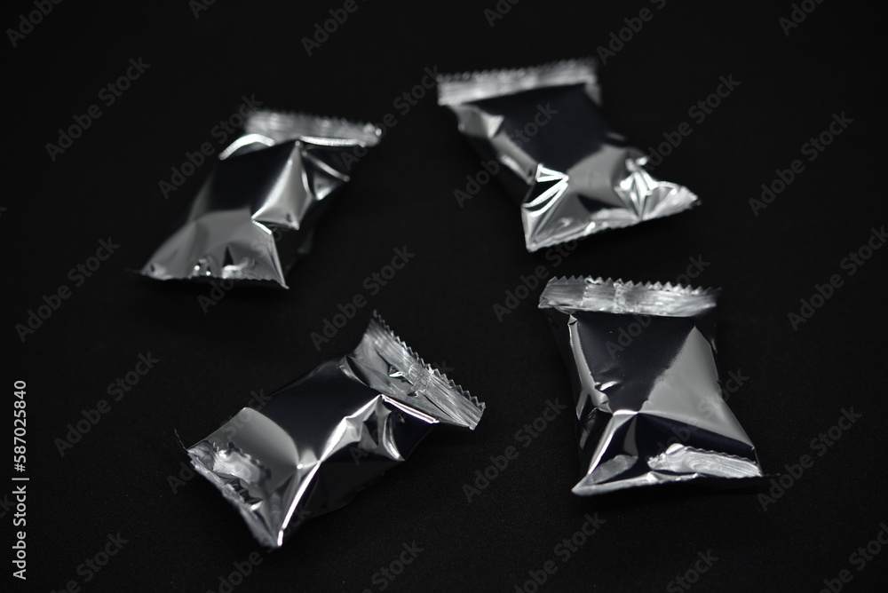 Candy in shiny blisters on a black background. Candy in a shiny package ...