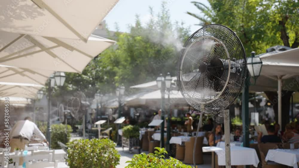 Fan with water spray in restaurant refreshes the air for visitors in ...