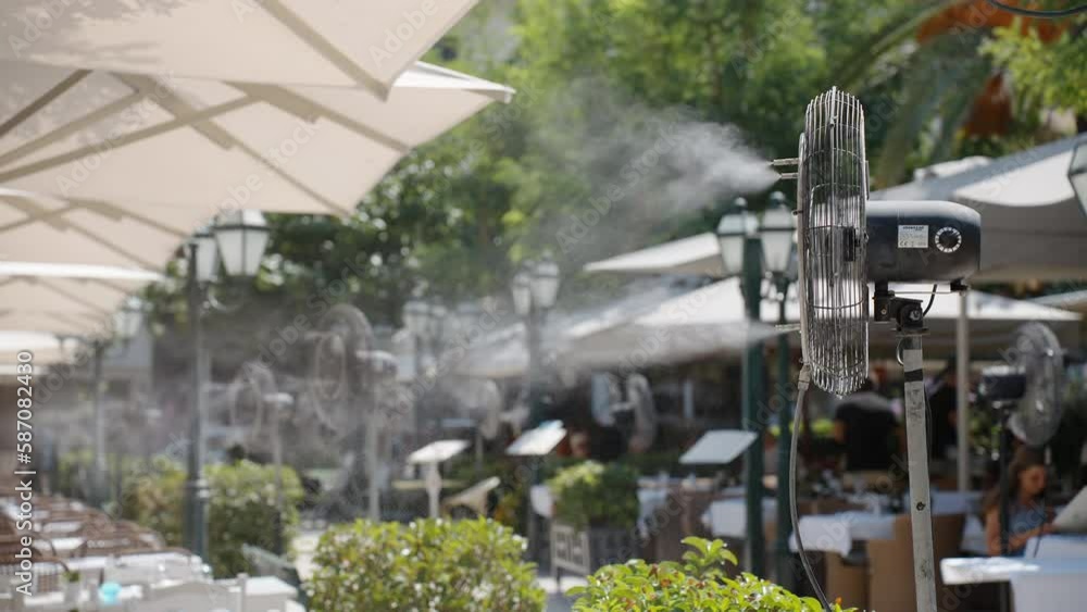 Fan with water spray in restaurant refreshes the air for visitors in ...