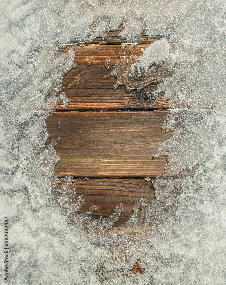 Ice frame or sheets of thin ice surround wood slats of lumber. Wet and ...