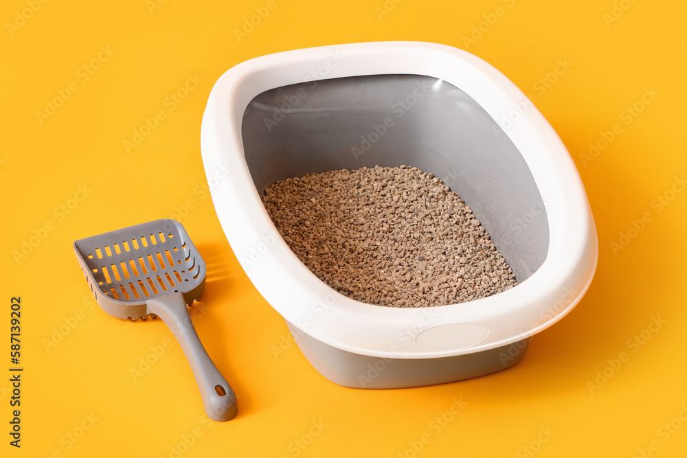 Litter box for cat and scoop on yellow background Stock Photo | Adobe Stock