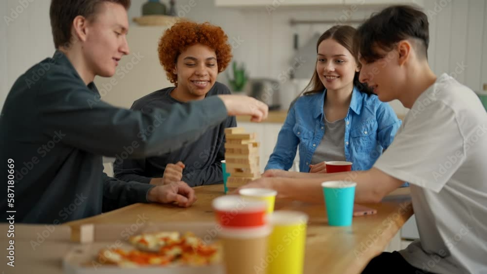Friends playing leaning tower board game at home. Friends take turns ...