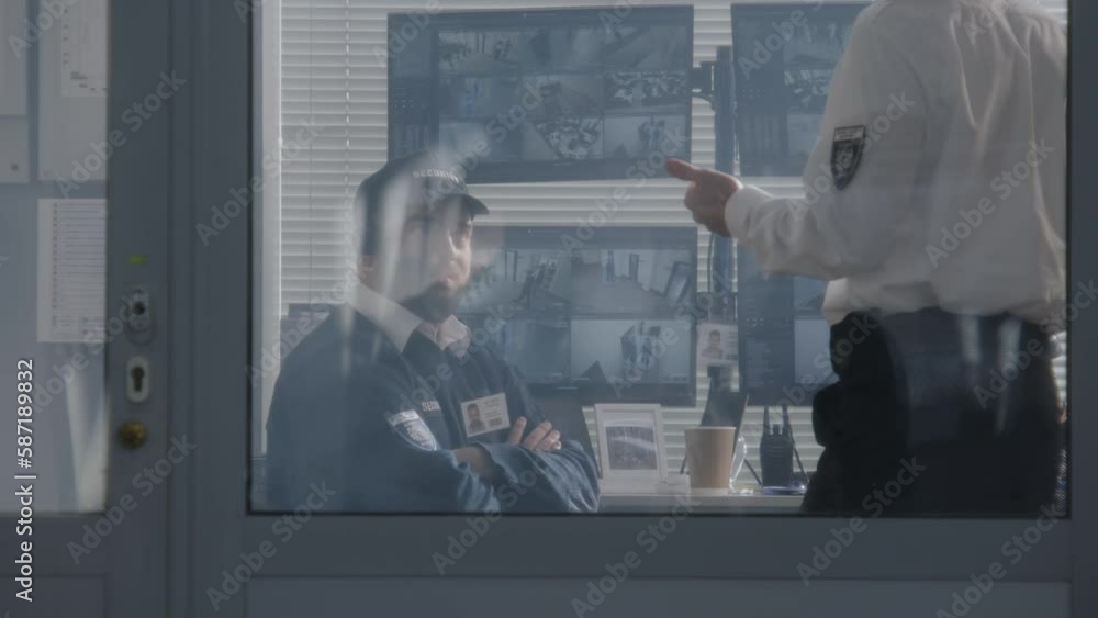 Security officers talk in surveillance room while monitoring CCTV ...
