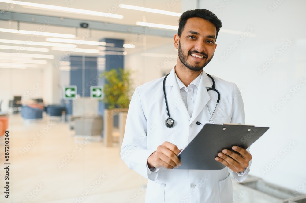 Portrait of male indian doctor wearing white coat having open door on ...