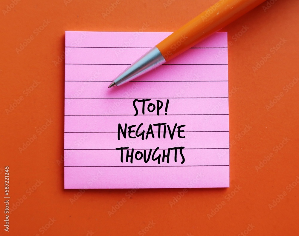 Pink note on orange background with pen written STOP NEGATIVE THOUGHTS ...