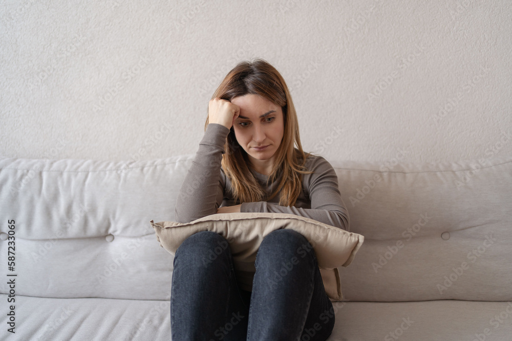 Depression concept. Portrait of sad woman sitting on sofa at home ...