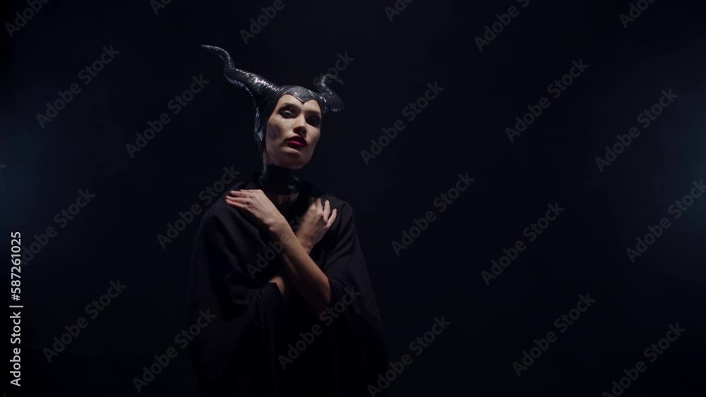An evil witch villain woman from a fairy tale with horns stands with ...