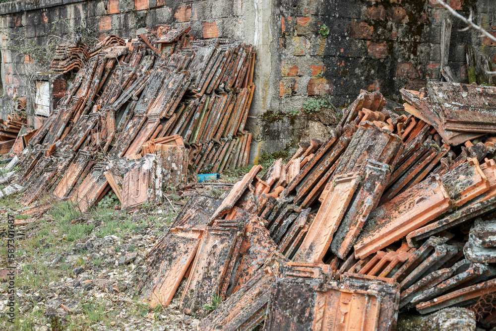 Detail of old roof tiles left at random in the environment, forgotten in time. Pollution of the ...