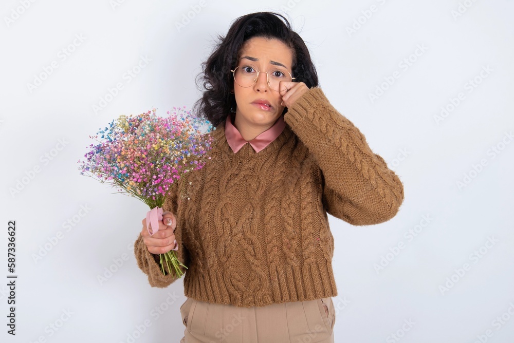 Disappointed dejected young woman holds big bouquet of nice flowers ...