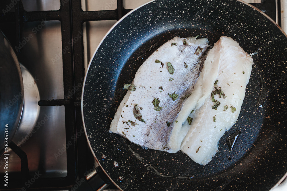 Foto de cooking fried hake fish in a frying pan, on a metal grill with ...