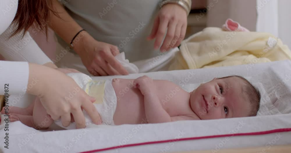 Mom and baby diaper changing. Mother's hands gently secure diaper lock ...