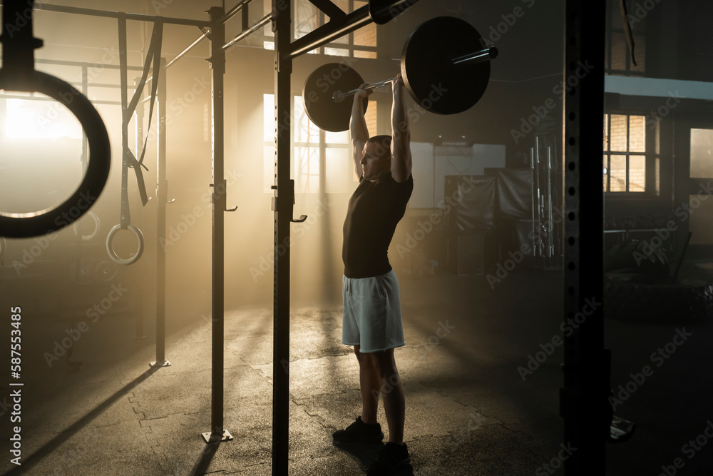 Crossfit bodybuilder lifting heavy barbell overhead at the gym ...