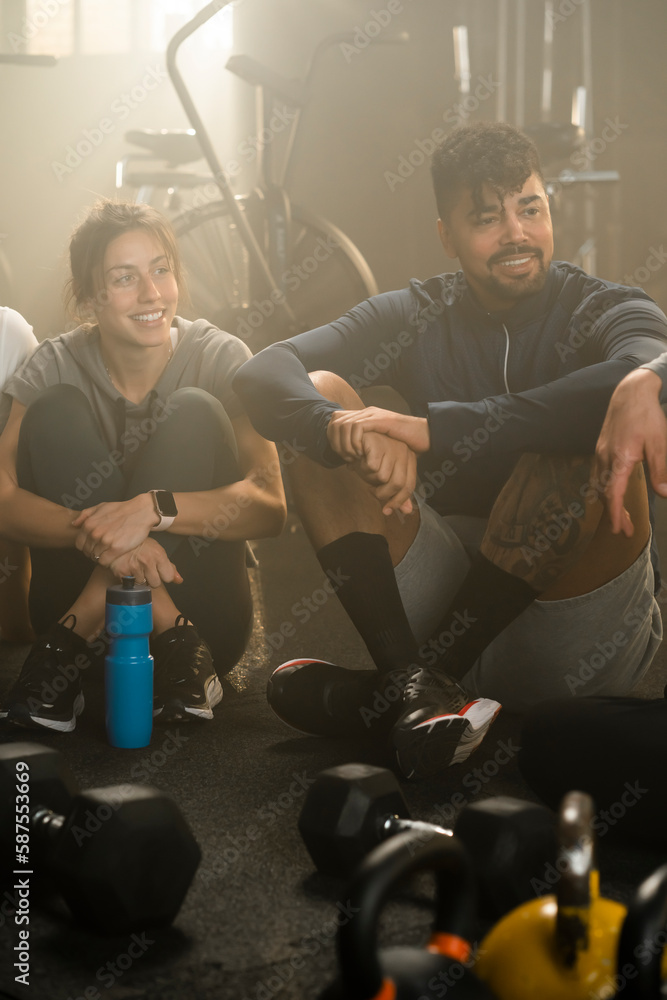 Happy friends taking a break from workout and chatting together during ...