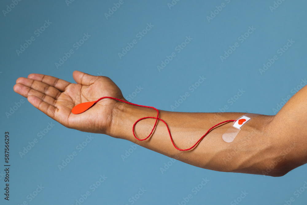 Arm of biracial man with heart sticking plaster and red string with ...
