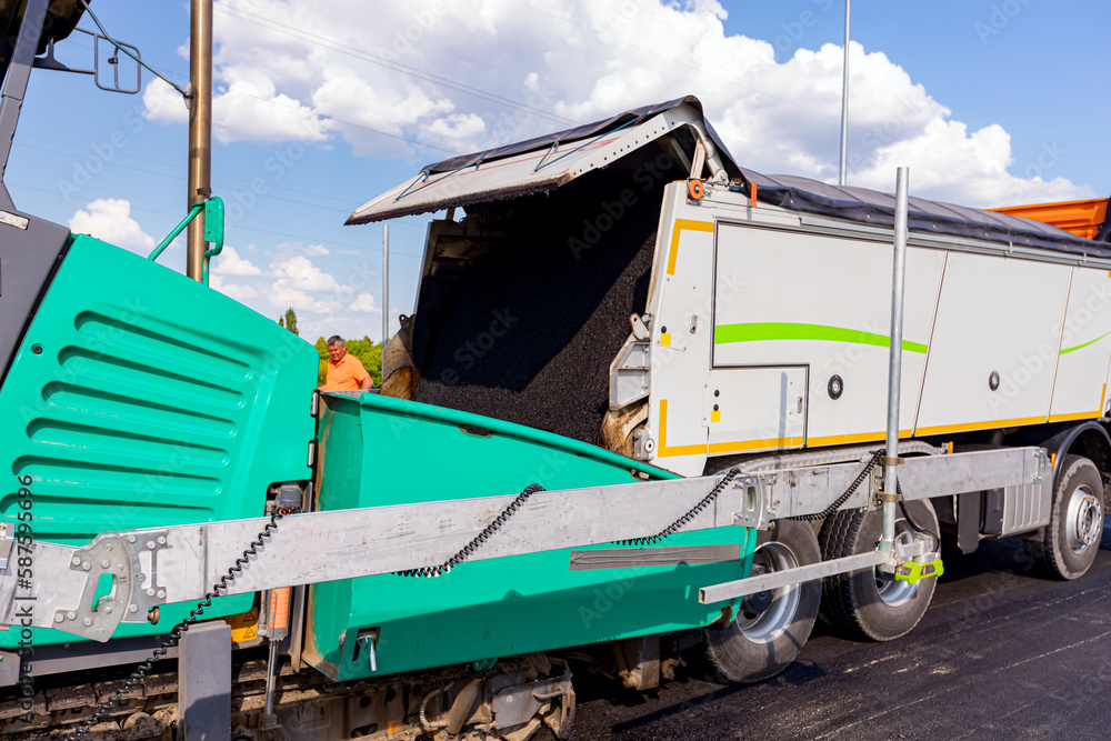 Truck is loading hot asphalt into spreader, tarmac road laying spreader ...
