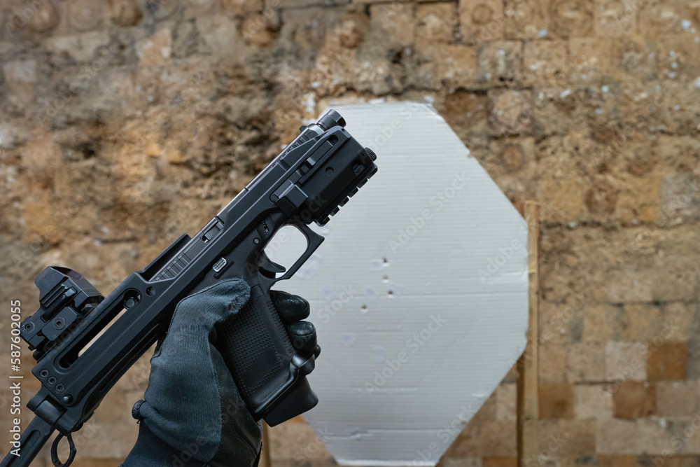 Tactical shooting from a pistol with a red dot sight at a target in a ...
